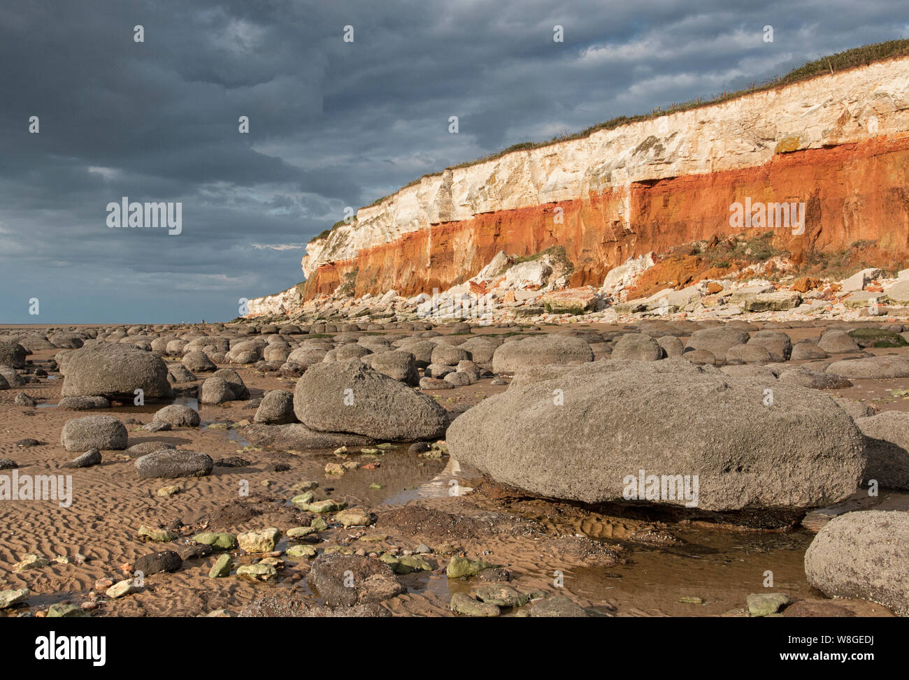 Hunstanton striped cliffs, with rounded boulders on the beach Stock ...