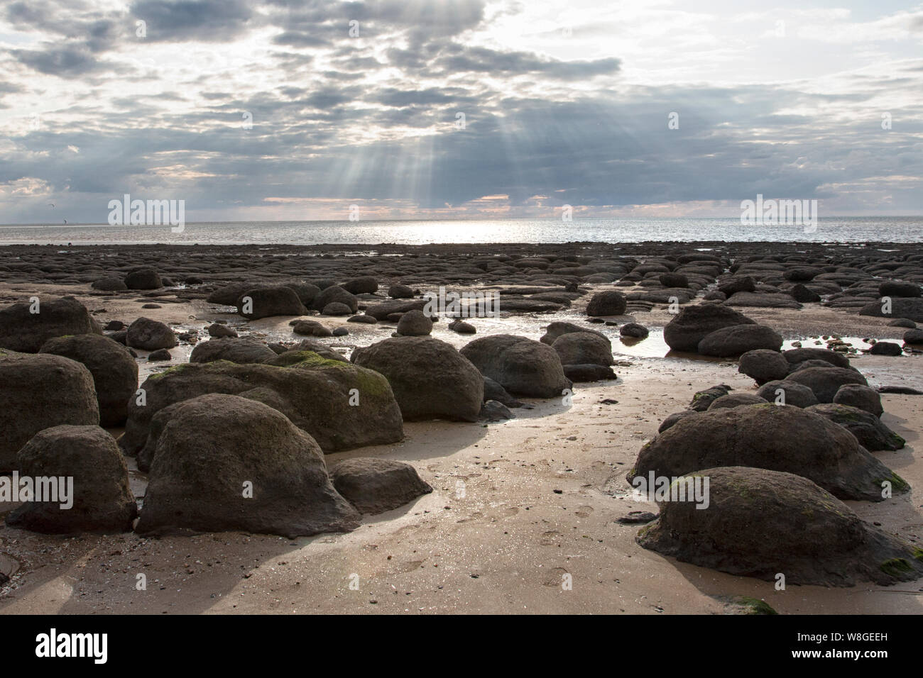 Distinctive large boulders in formation across the sandy beach of ...