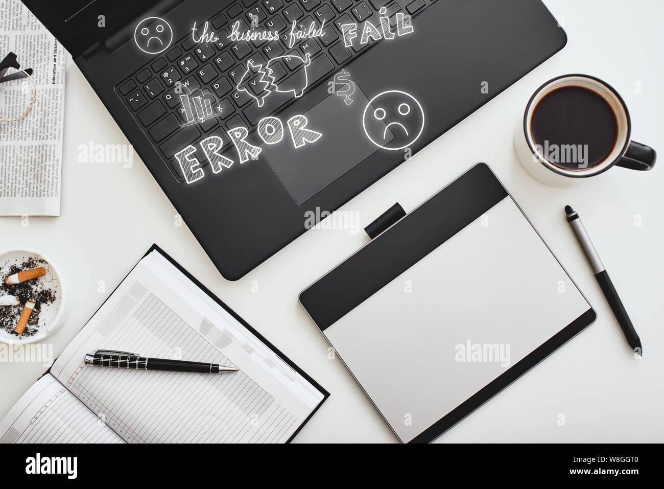 A cup of coffee, laptop, pen, ashtray with cigarette ends and notebooks ...