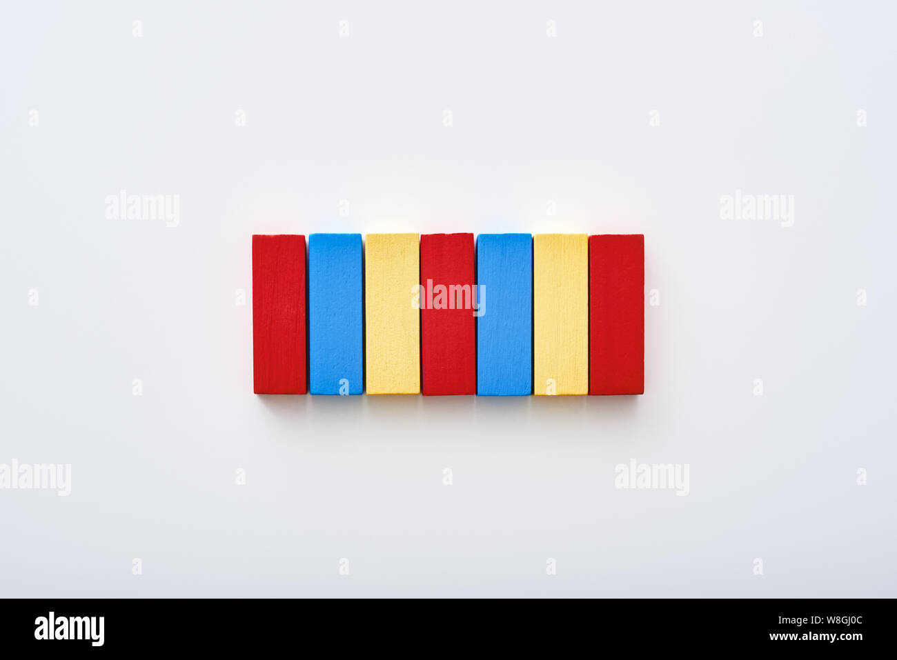 Red, blue and yellow wooden blocks of same height lying in a row ...
