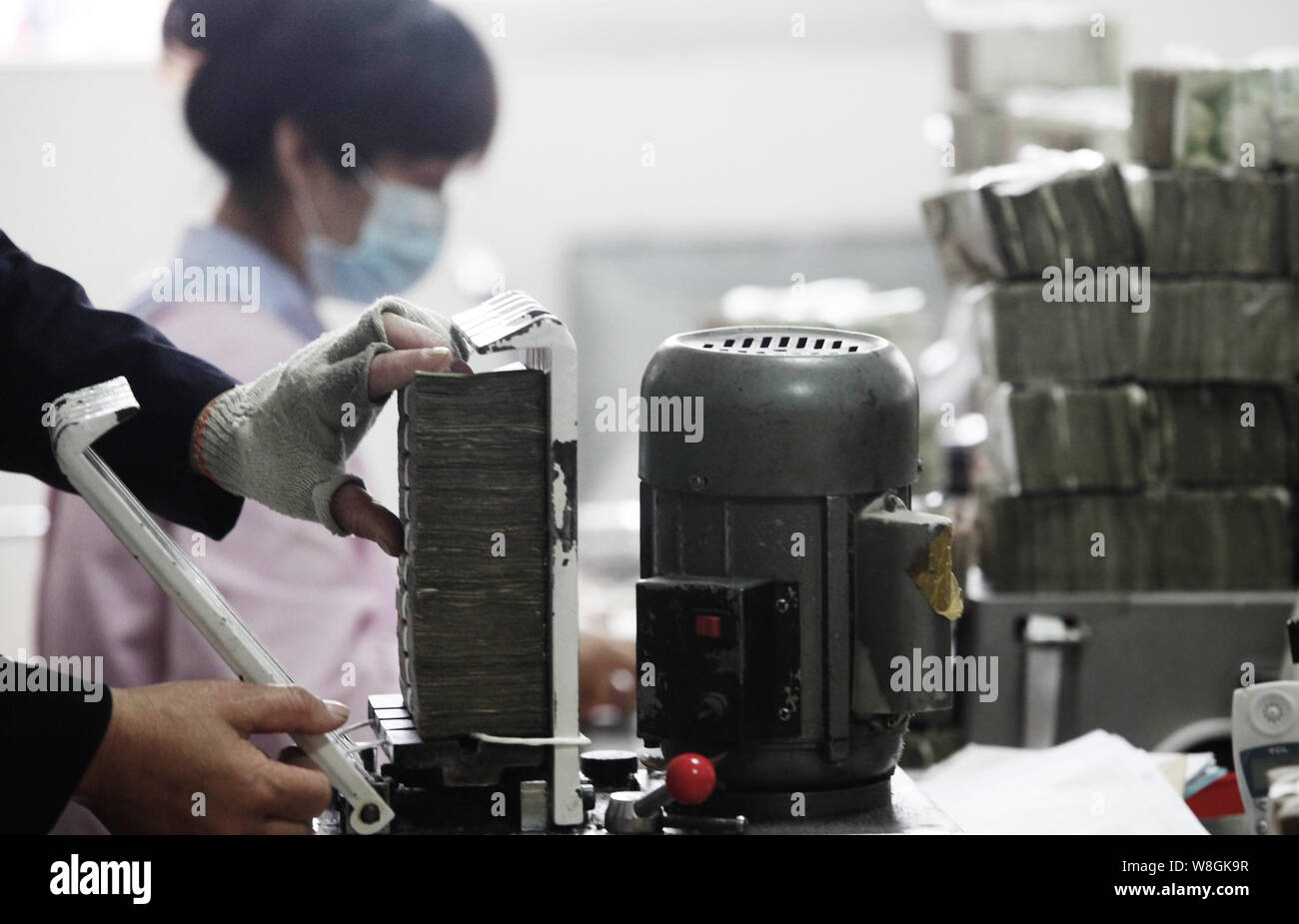 A Chinese cashier prepares to pack bundles of one-yuan banknotes at a ...