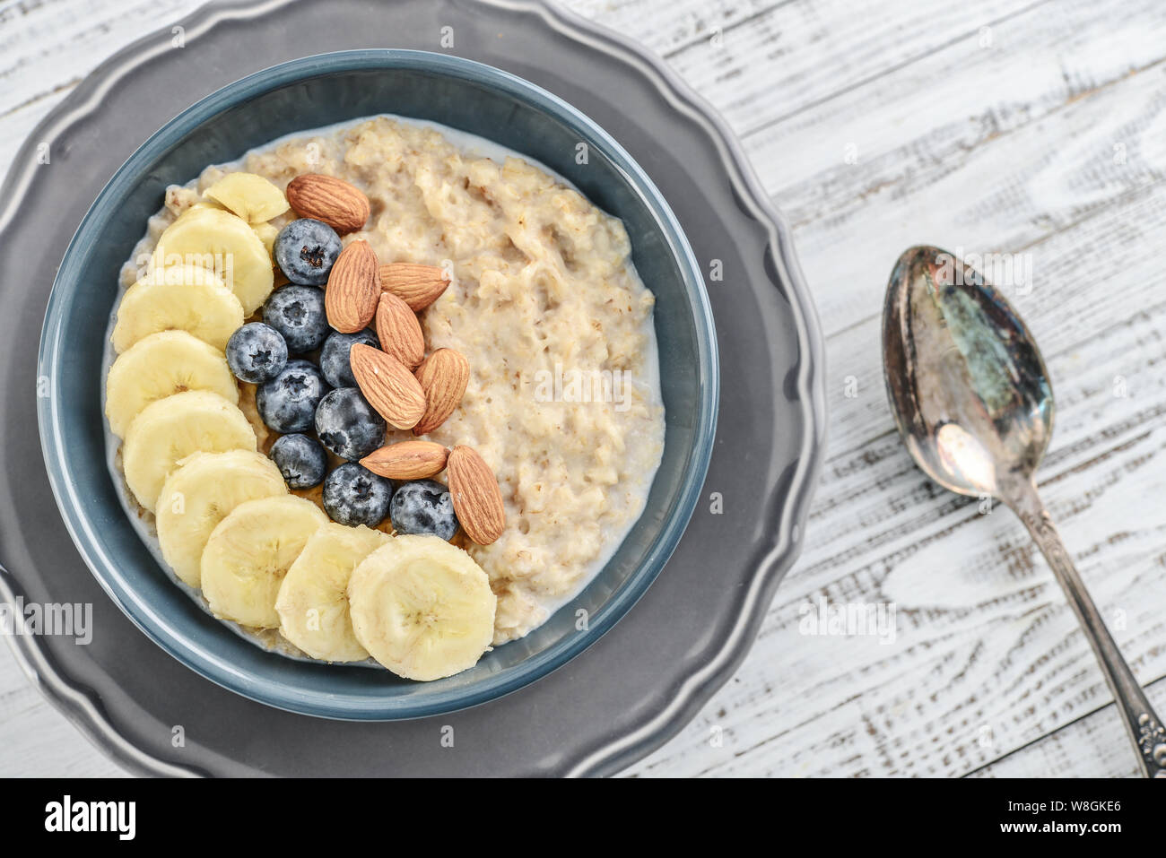 Bowl of oatmeal porridge with banana, blueberries, almonds, on wooden ...