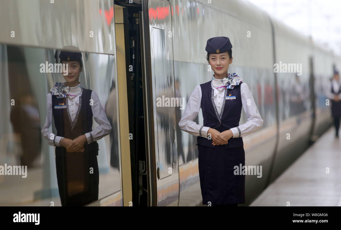 A Chinese attendant poses next to a CRH (China High-speed Railway ...