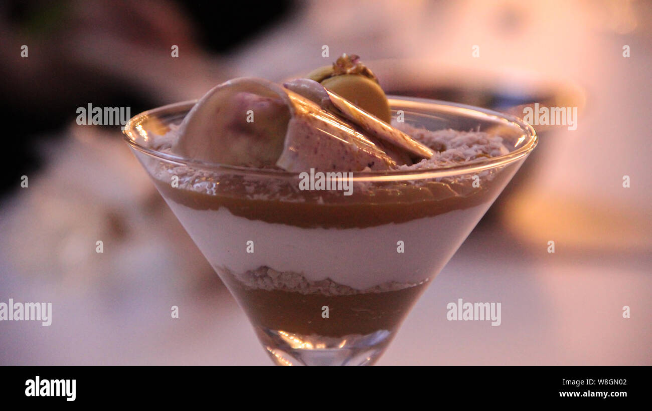 A cup with a mango pave, with coconut, a macaron, peach icing, white ...