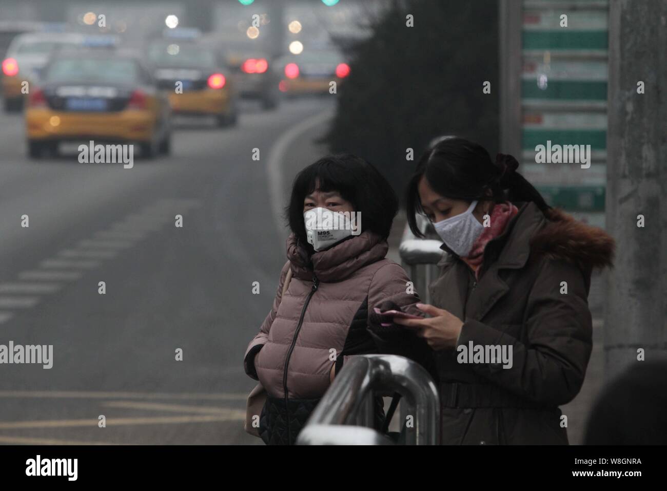 Pedestrians wearing face masks are pictured on a street in heavy smog ...