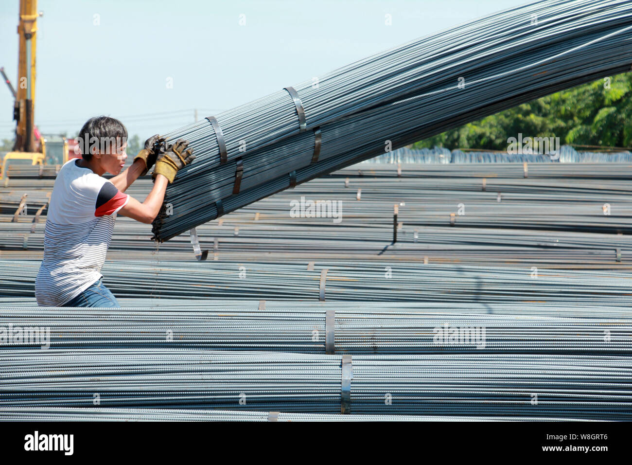 --FILE--A Chinese worker directs a crane to lift reinforcing steel rods ...