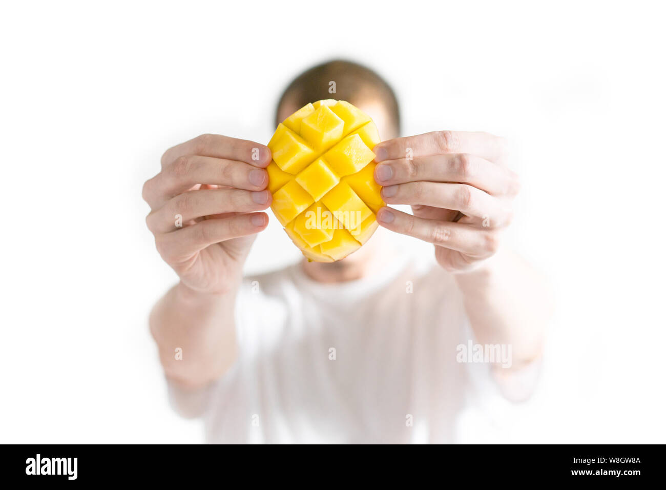 Man holds an open mango in front of him face. Guy shows sliced and ...