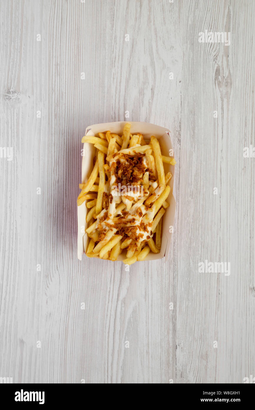 Top view, french fries with cheese sauce and fried onion in a paper box ...