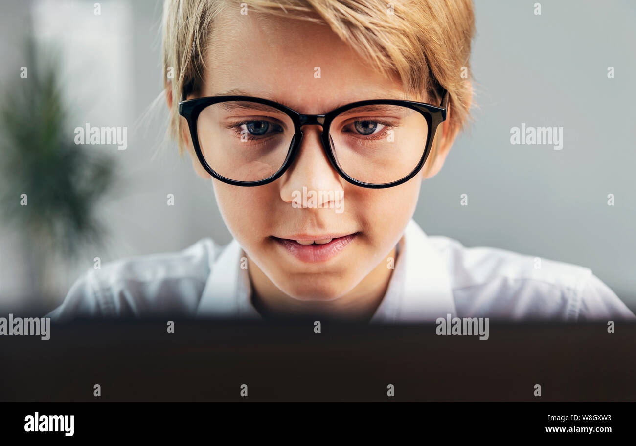 Concentrated boy in glasses gazing at the computer screen Stock Photo ...