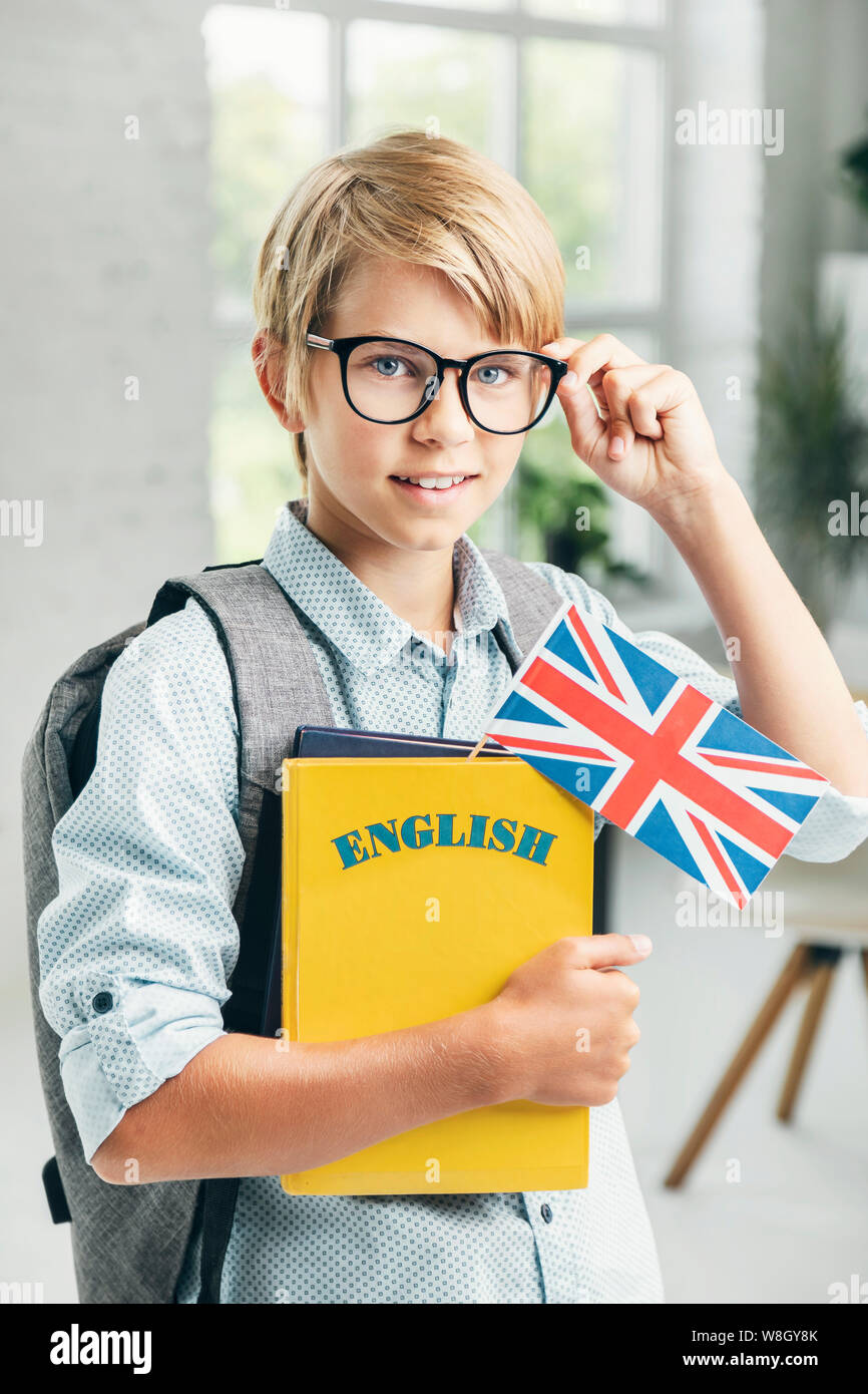 Smart schoolboy with English books adjusting glasses Stock Photo - Alamy