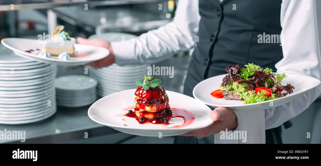 Waiter serving in motion on duty in restaurant. The waiter carries ...