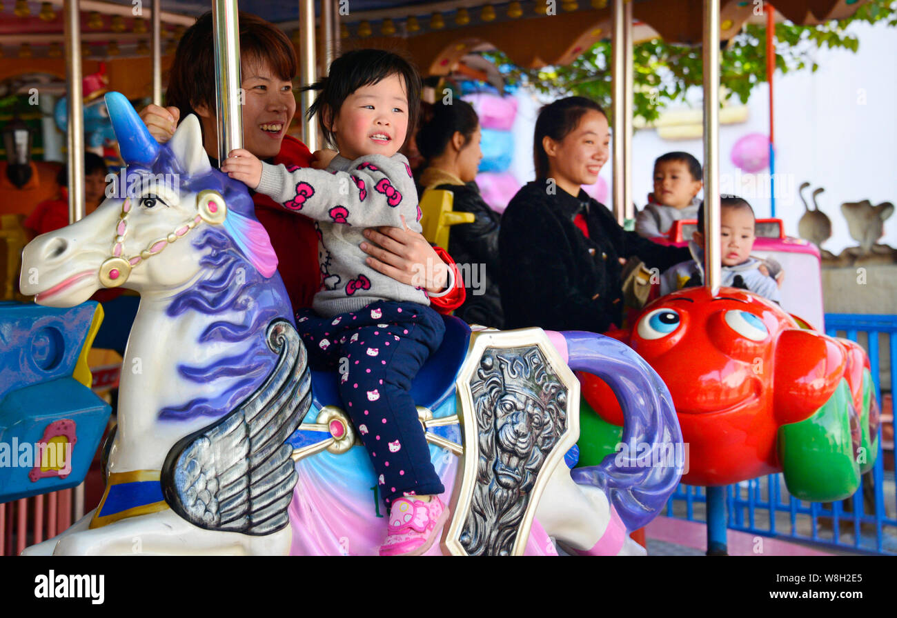 --FILE--Chinese mothers accompany their children on a carousel at a ...
