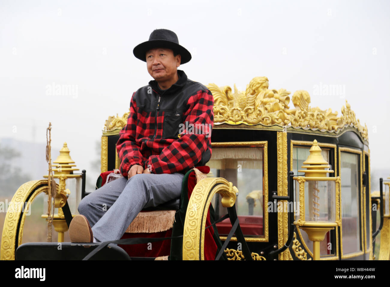 A Chinese man sits on his own carriage pulled by two horses on a road ...