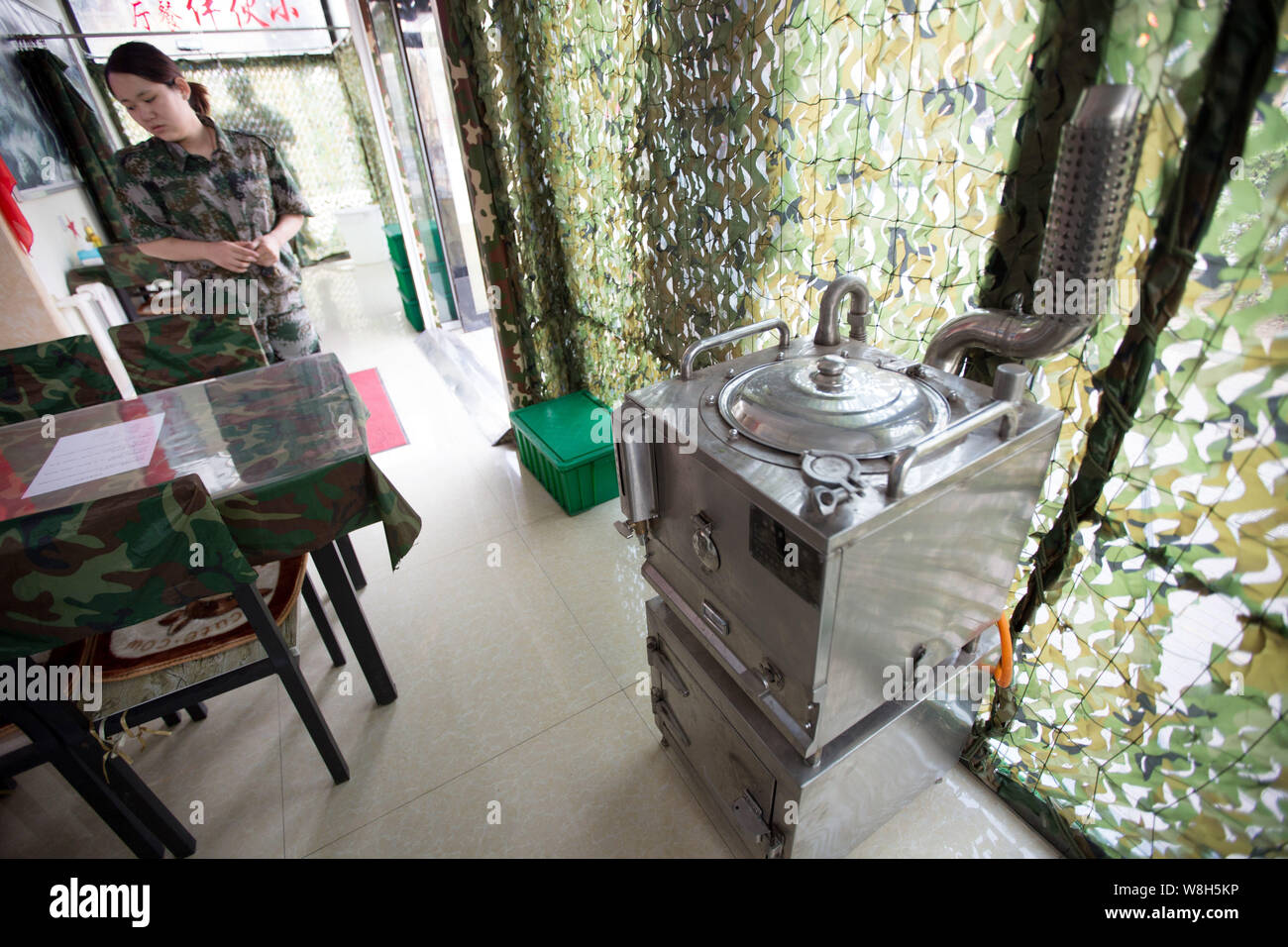 A Chinese waitress stands inside the military-themed restaurant whose ...