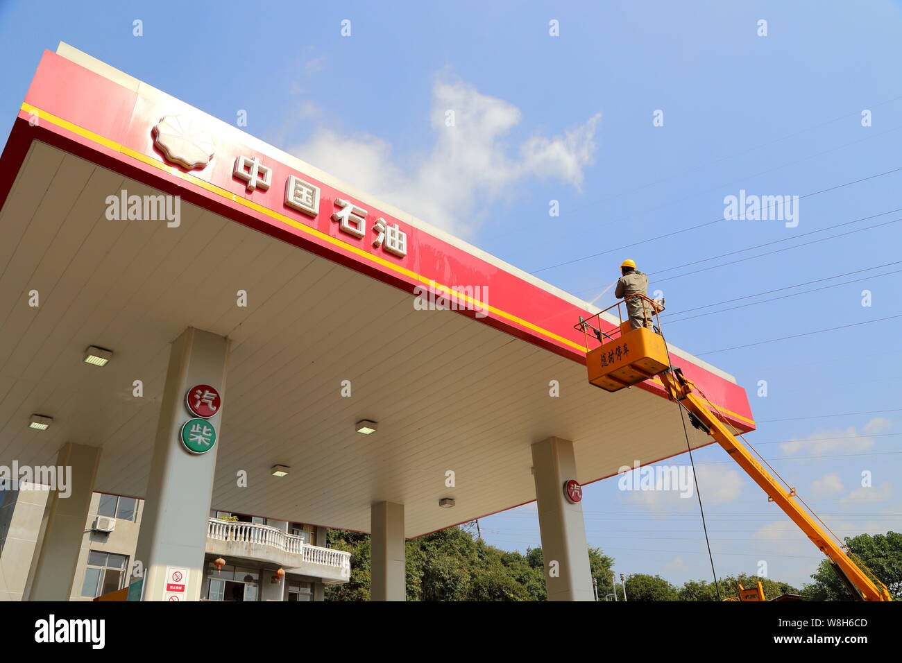 --FILE--A Chinese worker cleans the signboard at a gas station of ...