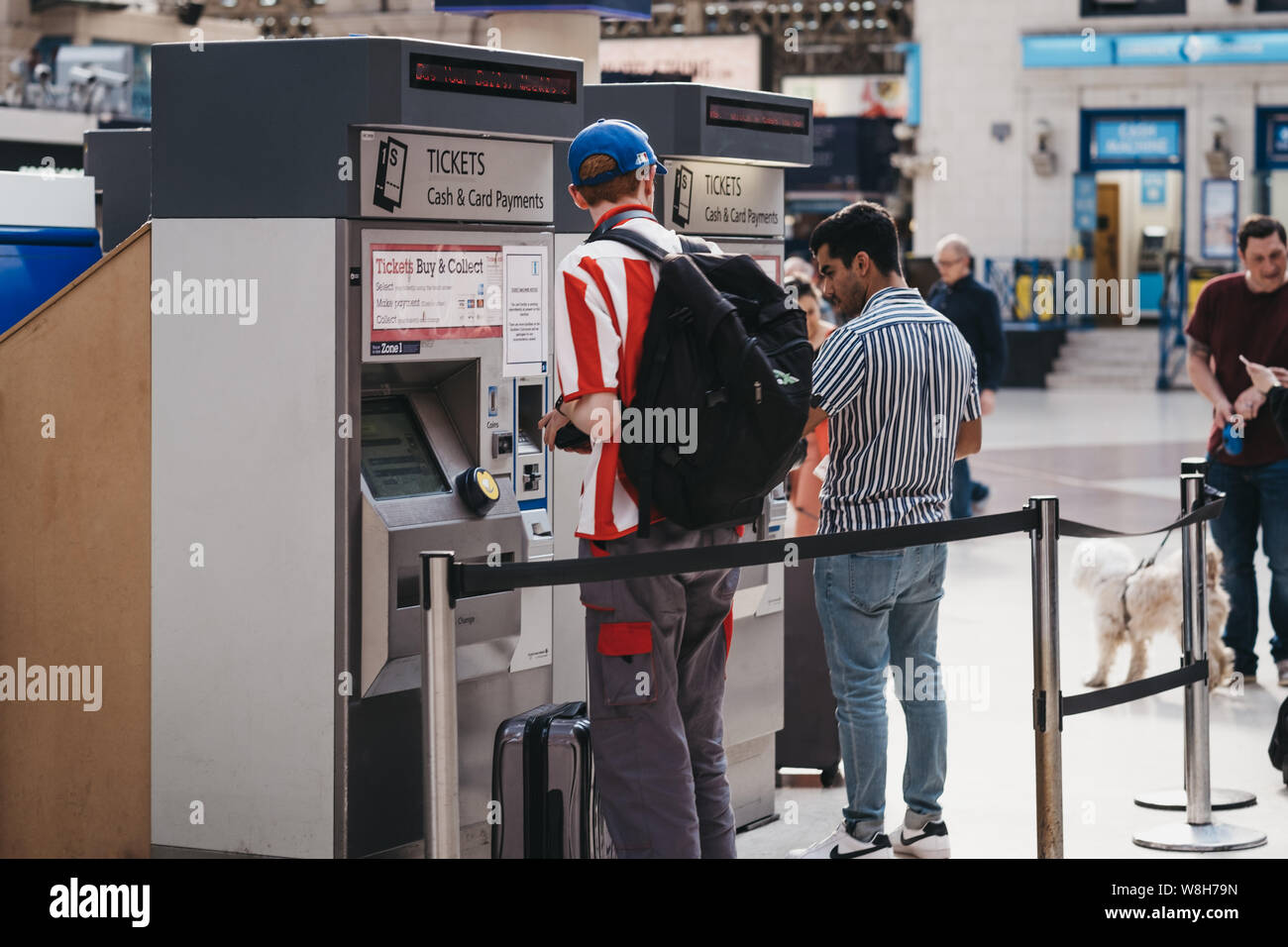 London, UK - July 16, 2019: People buying train tickets from a self ...