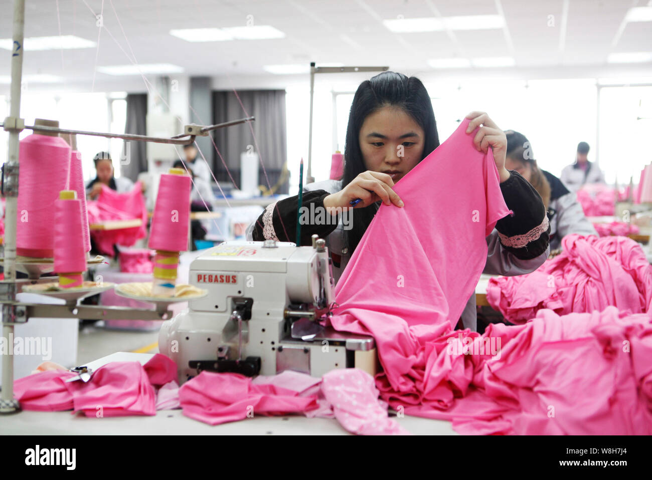 --FILE--A female Chinese worker sews clothes at a garment factory in ...