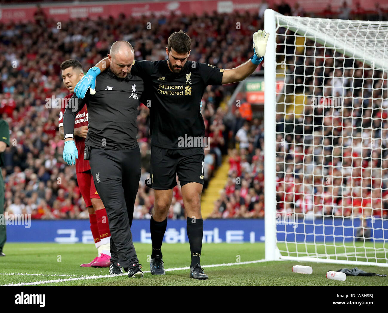 Liverpool goalkeeper Alisson (right) leaves the pitch after picking up ...