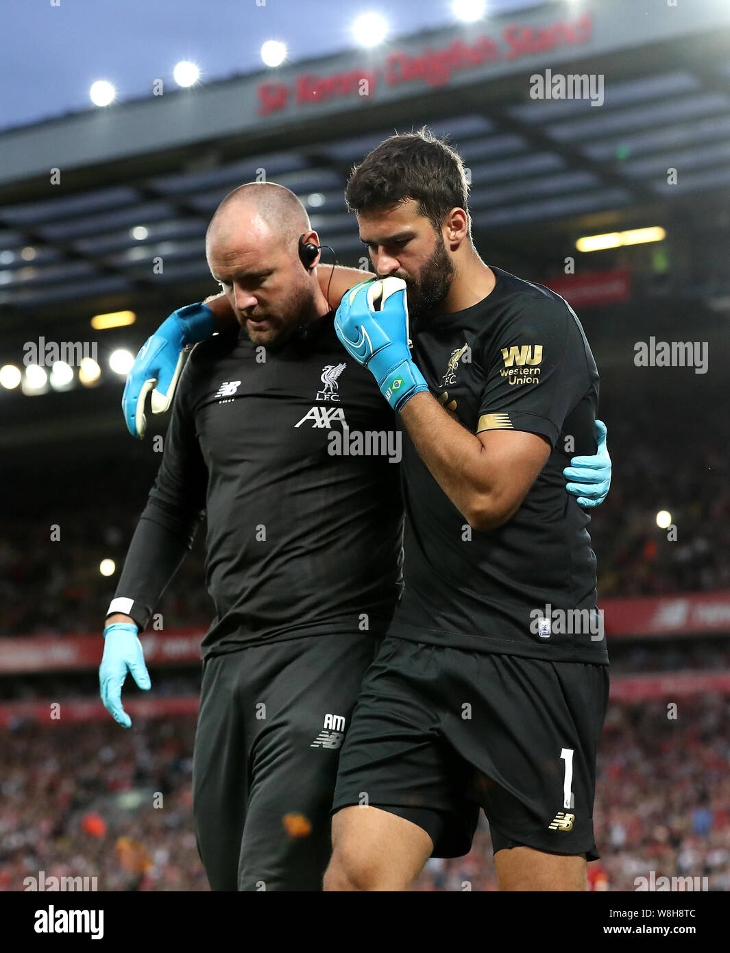 Liverpool goalkeeper Alisson (right) leaves the pitch after picking up ...