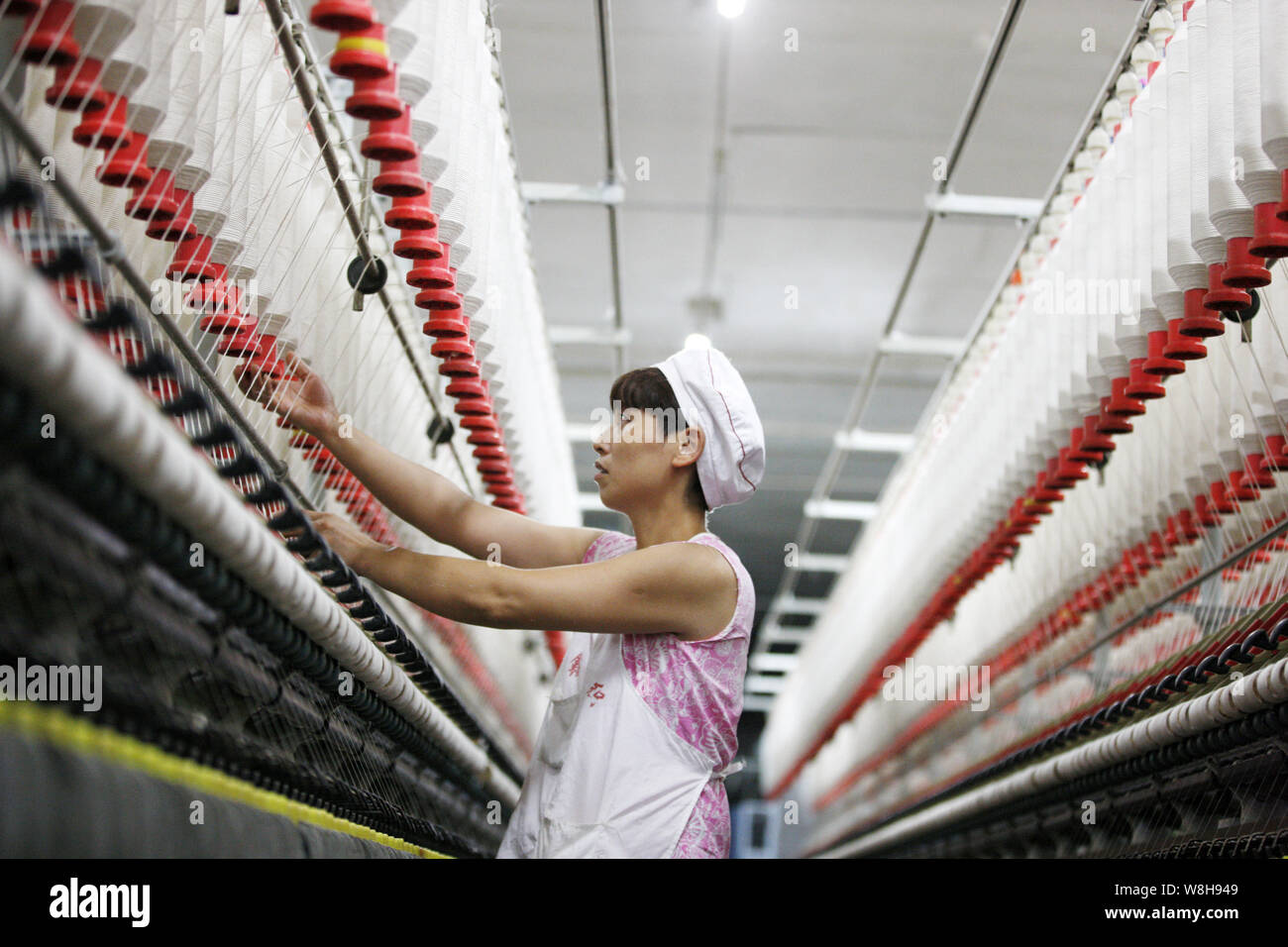 A female Chinese worker handles production of yarn to be exported to Southeast Asia on a ...
