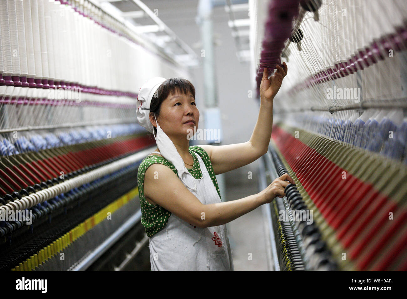 A female Chinese worker handles production of yarn at a garment factory ...