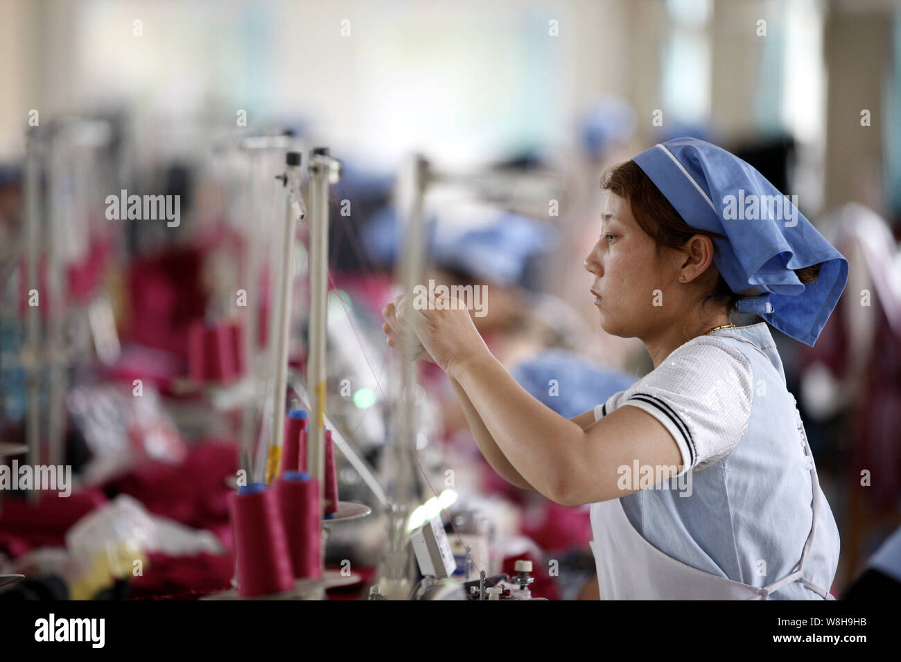 --FILE--A female Chinese worker sews clothes at a garment factory in Huaibei city, east China's ...