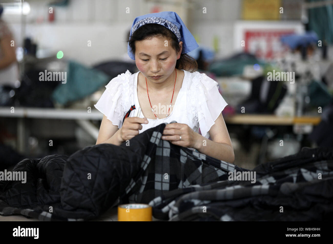 --FILE--A female Chinese worker sews clothes at a garment factory in ...