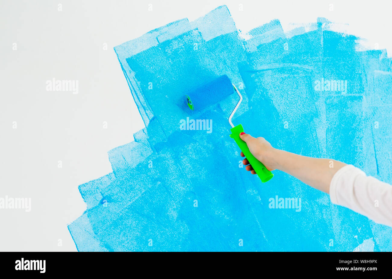 blue color painting wall with roller in hand Stock Photo - Alamy