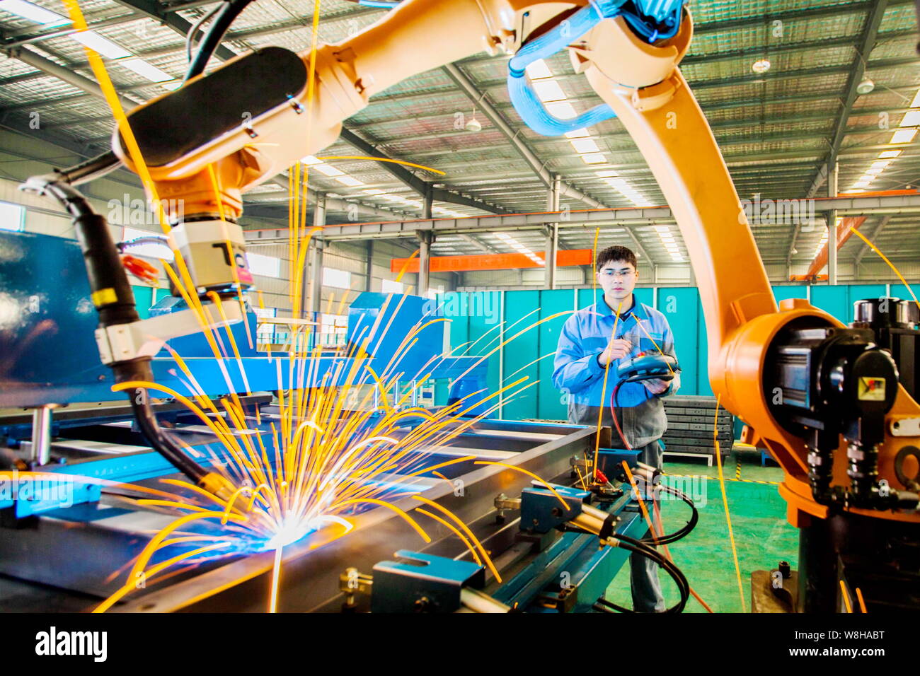 --FILE--A Chinese worker controls a robot arm to weld components of ...