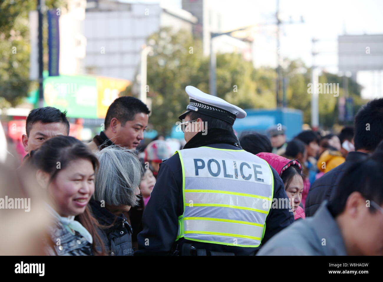 --FILE--A Chinese police officer stands guard amongst a crowd of ...