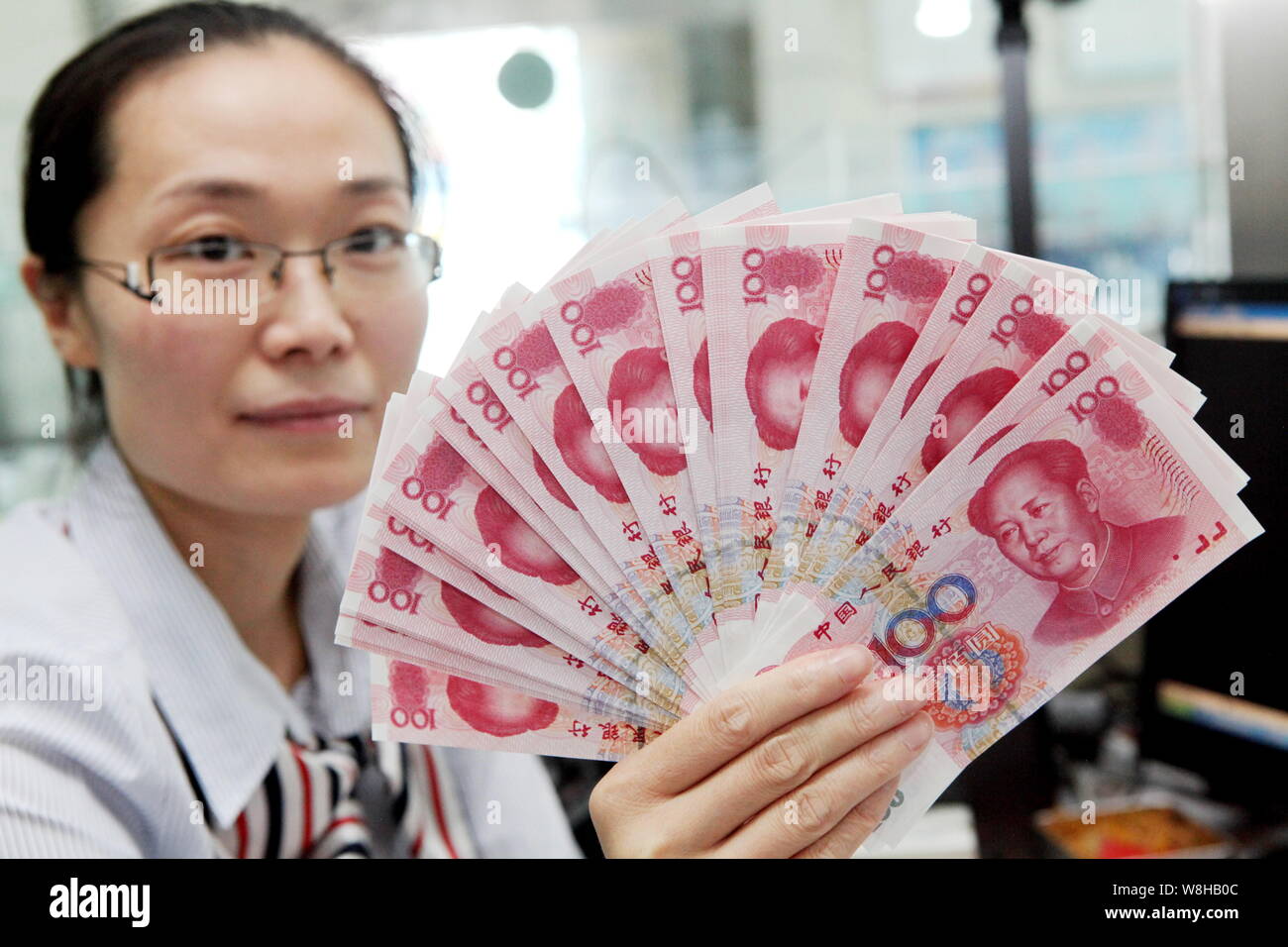 --FILE--A Chinese clerk shows RMB (renminbi) yuan banknotes at a bank ...