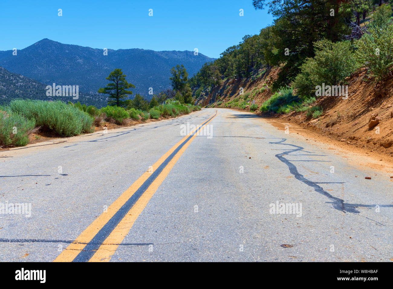 Narrow down hill straight mountain road with double yellow lines under ...