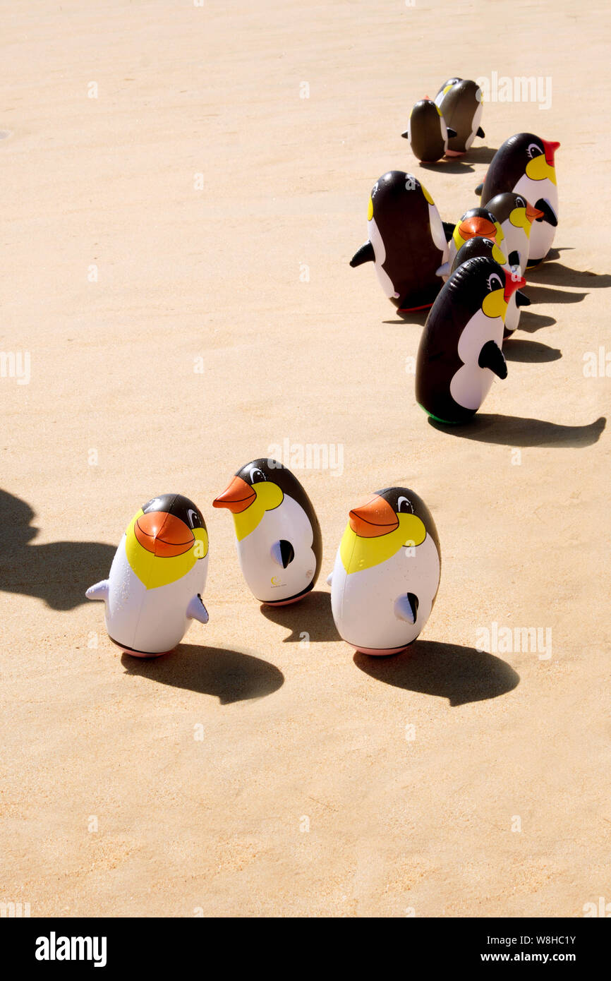 ten inflated blow up penguins on the sea shore, half of them are in the ...