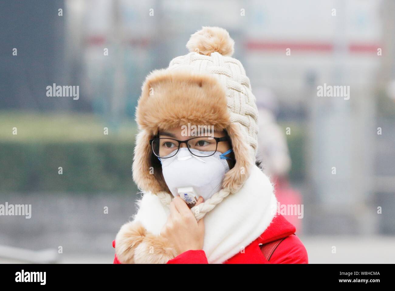 A pedestrian wearing a face mask walks on a street in heavy smog in ...