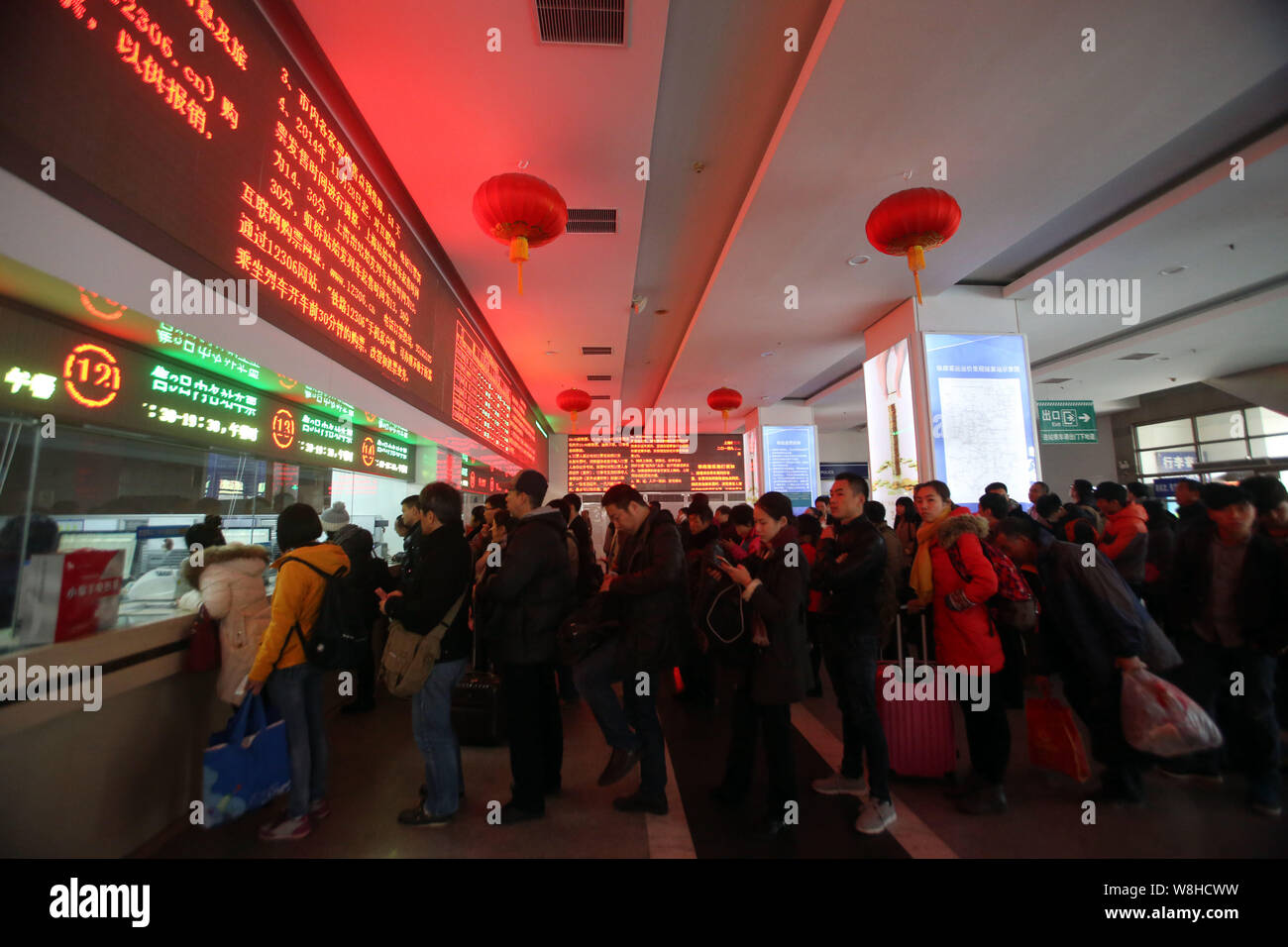 Chinese passengers queue up to buy train tickets in a ticket office at ...