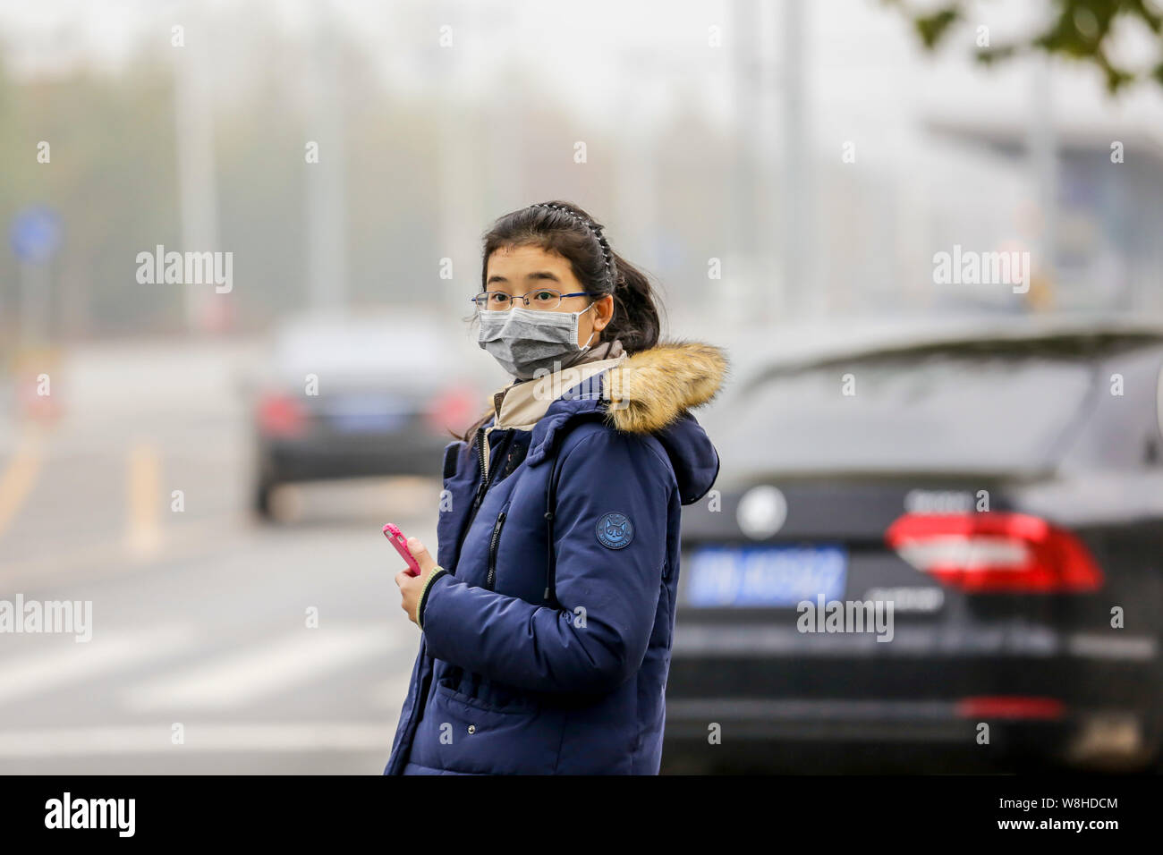 A pedestrian wearing a face mask is pictured on a street in heavy smog ...