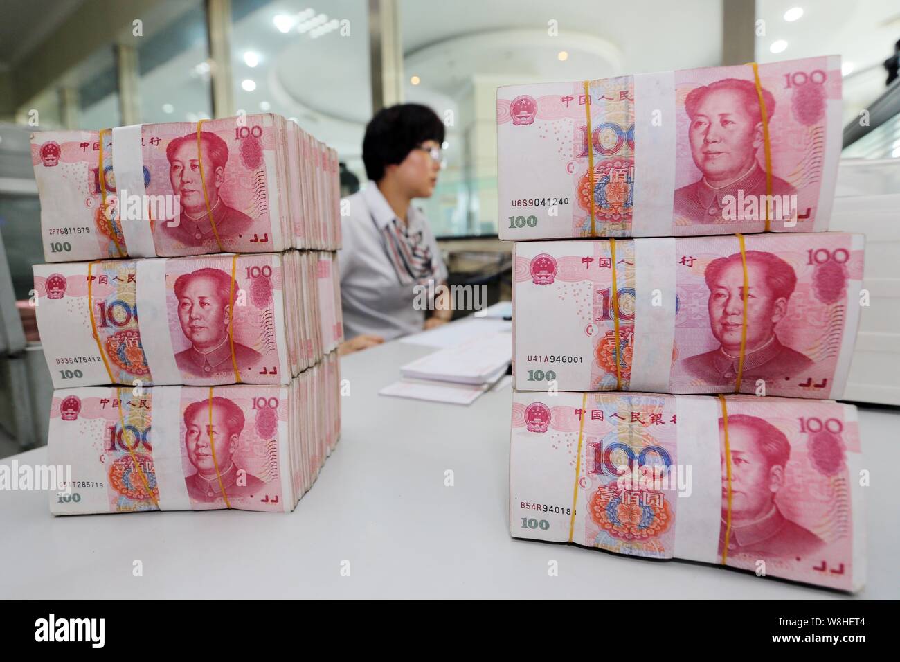 --FILE--A Chinese clerk works next to bundles of RMB (renminbi) yuan ...