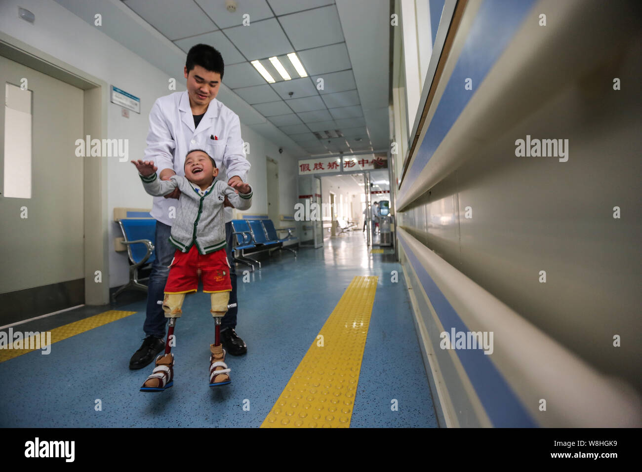 A physiotherapist carries the four-year-old legless boy Xiao Feng ...
