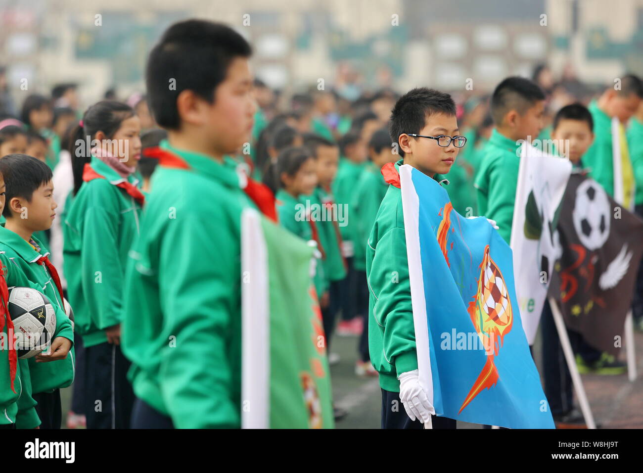 Young Chinese students pose with footballs or team flags at the opening ...