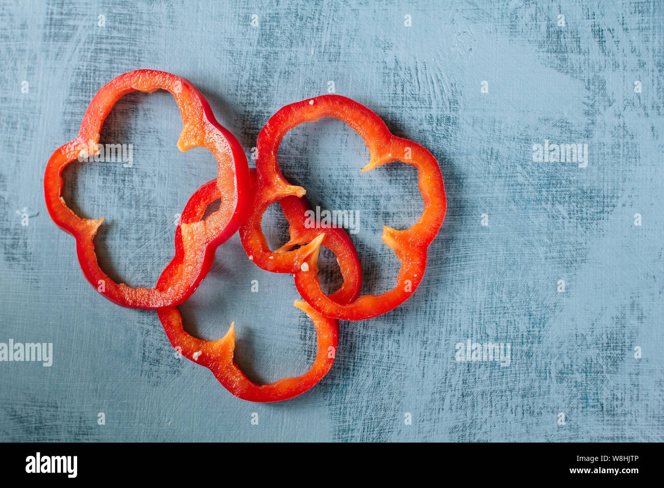 A set of sliced pieces of red pepper on a blue wooden background with a ...