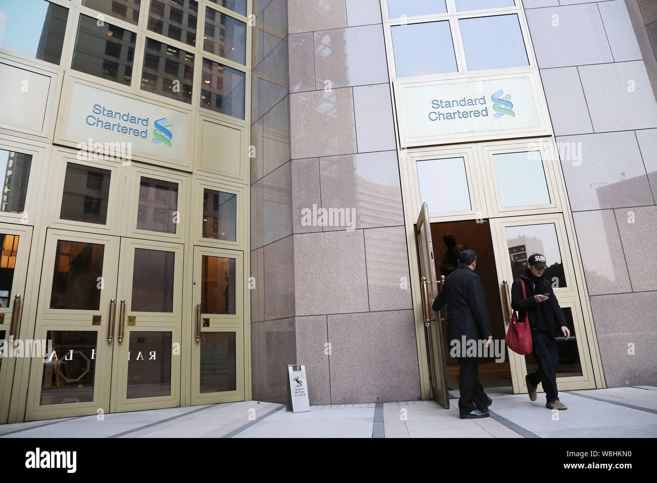 --FILE--People walk out from the Standard Chartered Building in Central ...