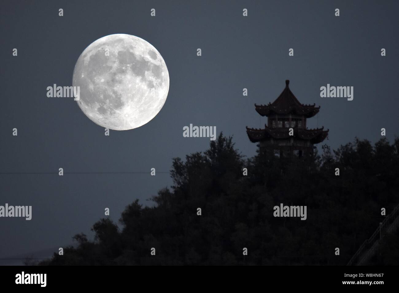 View of the full moon over a tower in a park at night on the Mid-Autumn ...