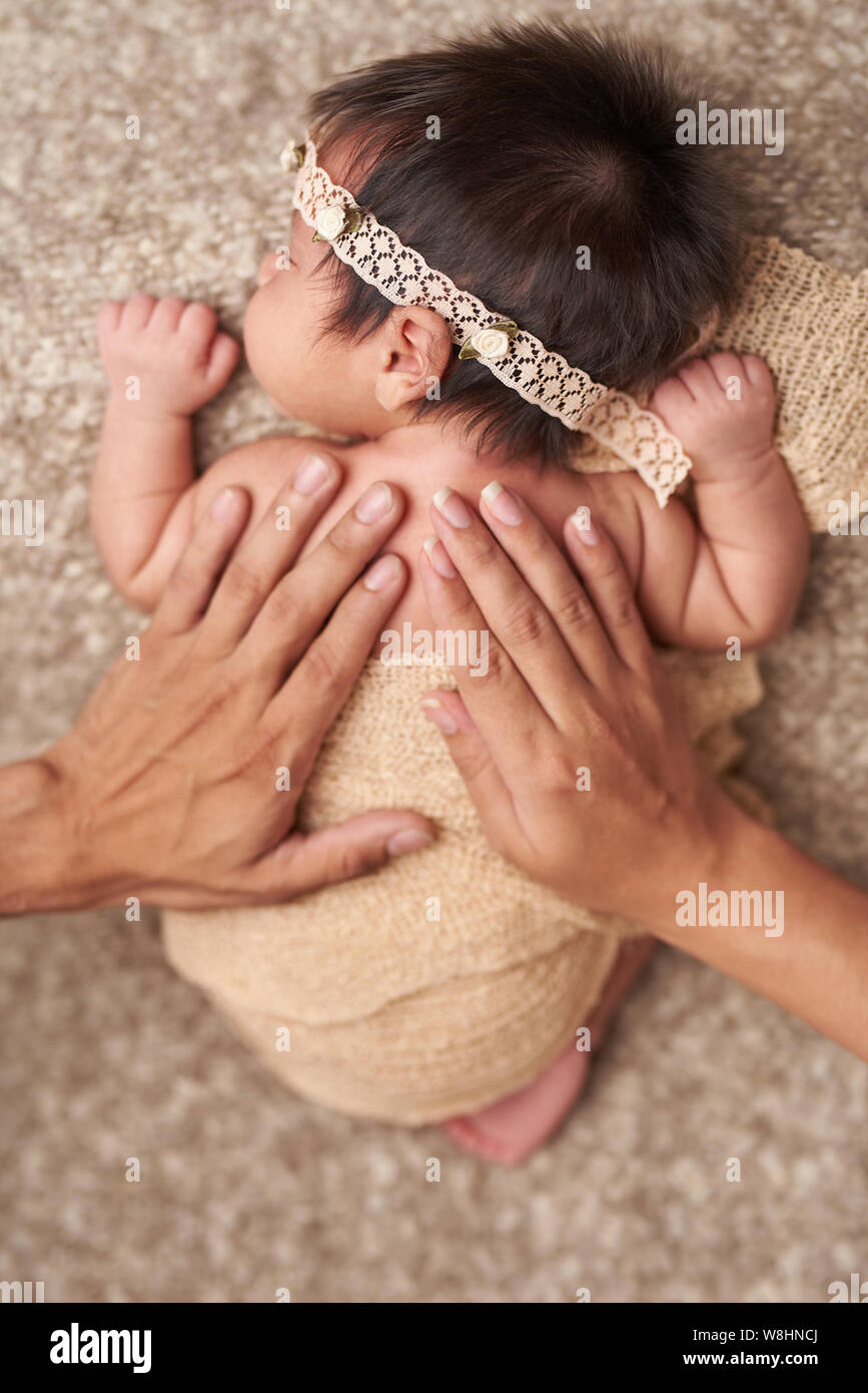 Parents hands tap kid back lying on soft brown blanket Stock Photo - Alamy