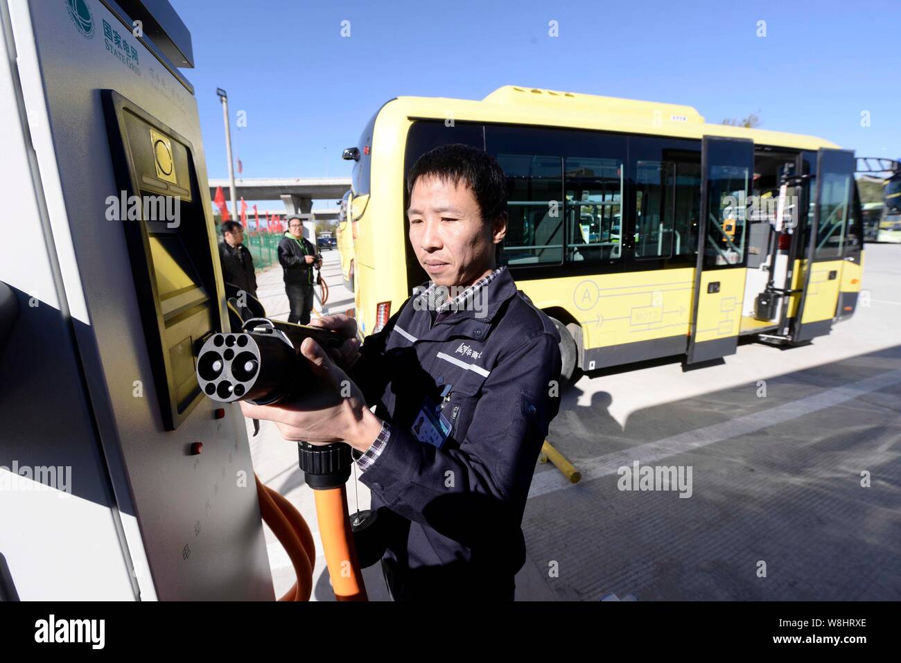 --FILE--A Chinese worker holds a plug to recharge an electric bus at a ...