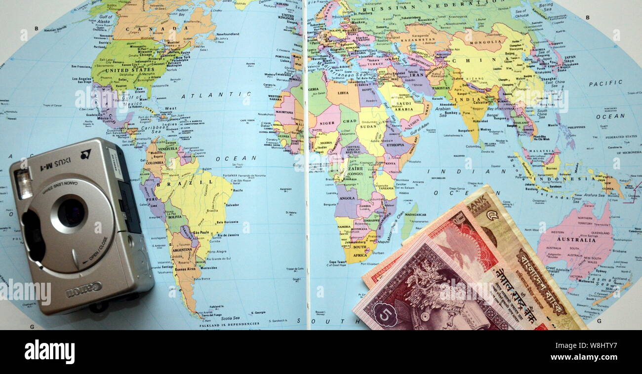 A vintage camera and foreign banknotes on an open atlas page showing a ...