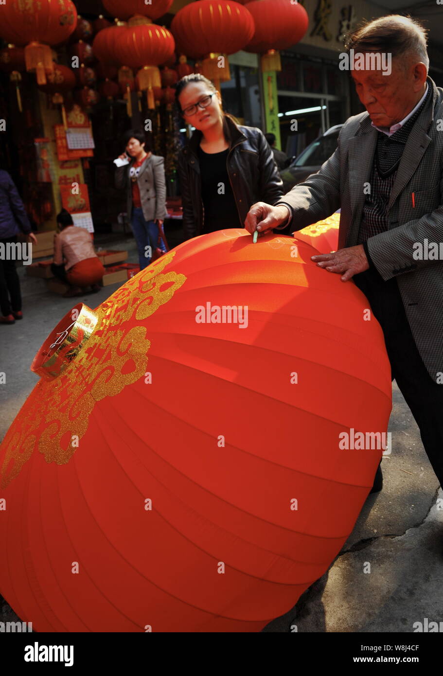 A Chinese worker prepares to write Chinese characters on a red lantern ...