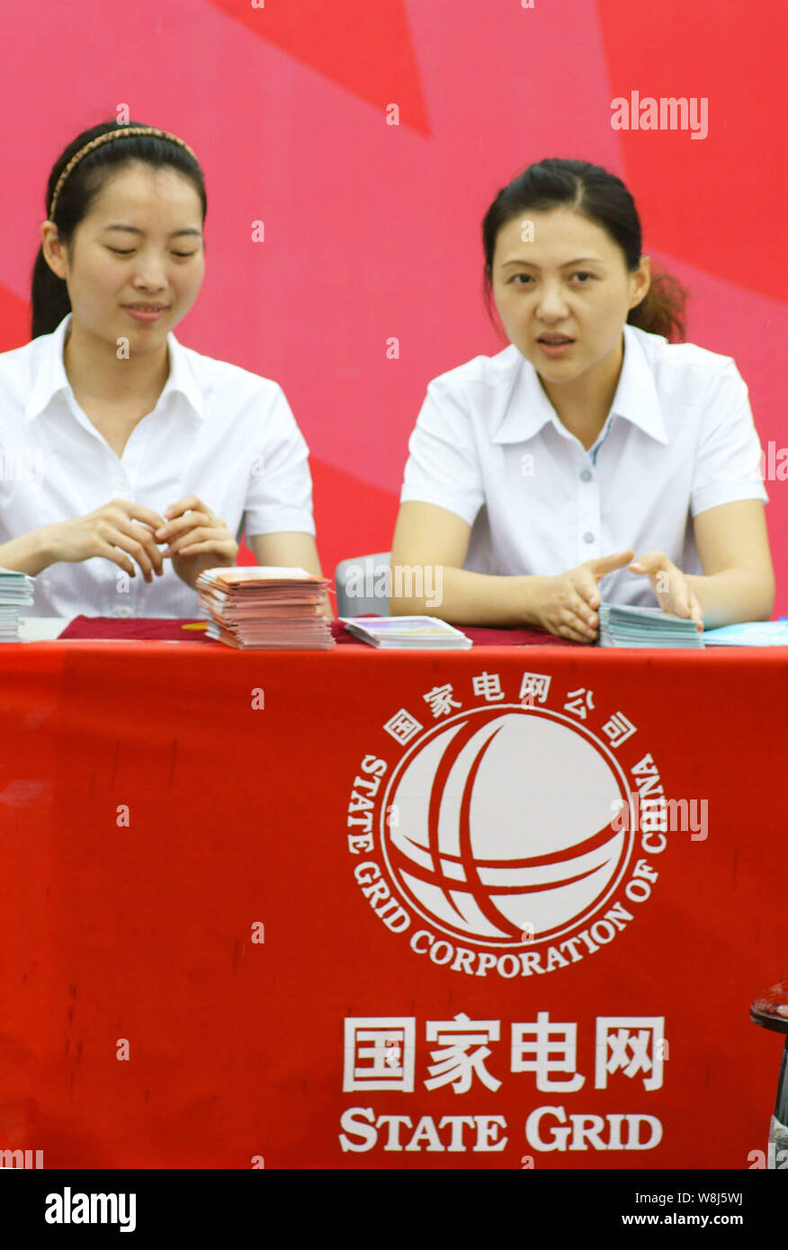 --FILE--Chinese employees are seen at the stand of State Grid ...