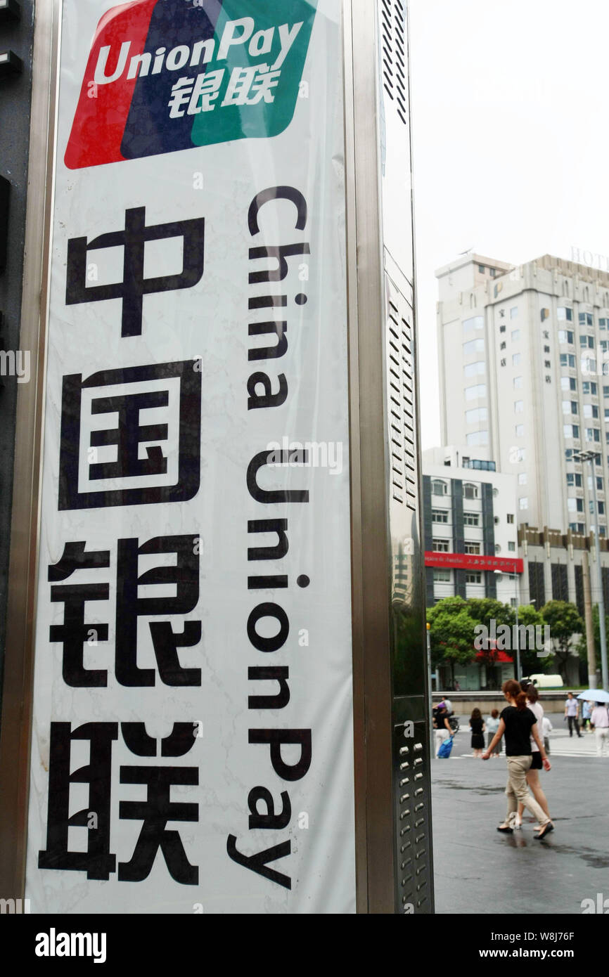 --FILE--Pedestrians walk past a signboard of China UnionPay in Shanghai ...