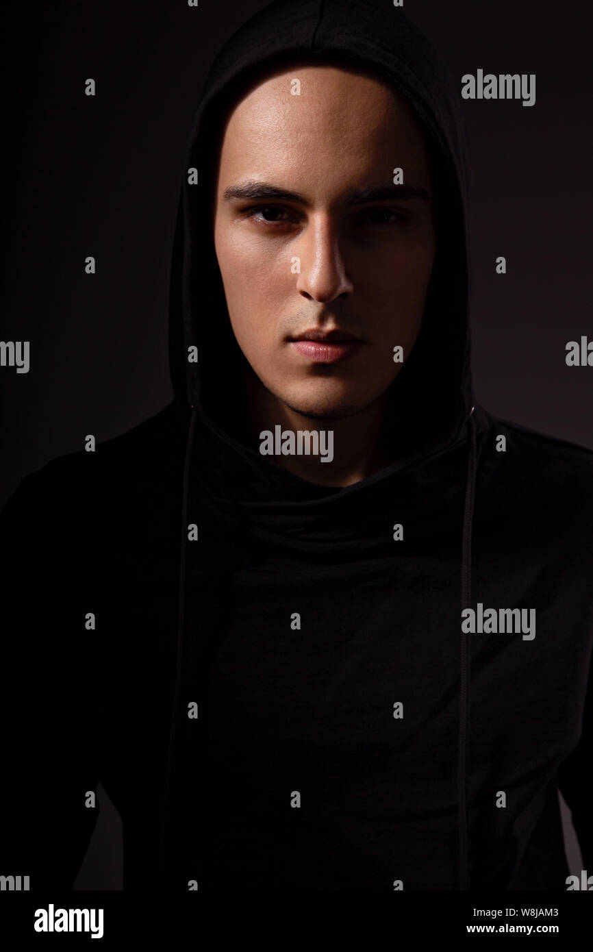 Mysterious angry man in black hoodie with hood on the head on dark ...