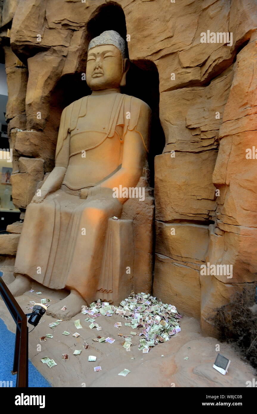 Banknotes thrown by believers are placed near Buddha statues to pray ...